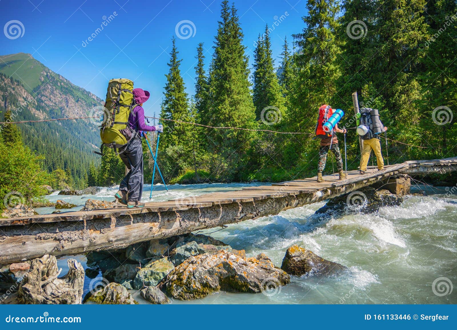 Hikers Crossing Over Wood Bridge Under Mountain River Stock Photo ...