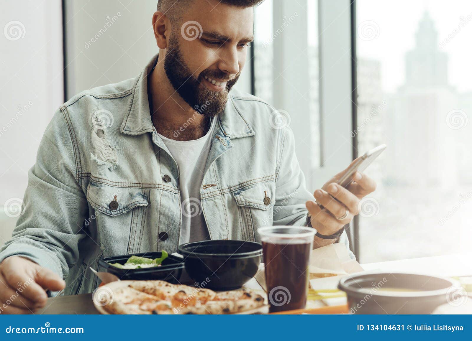 Hipster Guy Sits in Cafe at Table, Has Lunch, Using Smartphone. Man ...