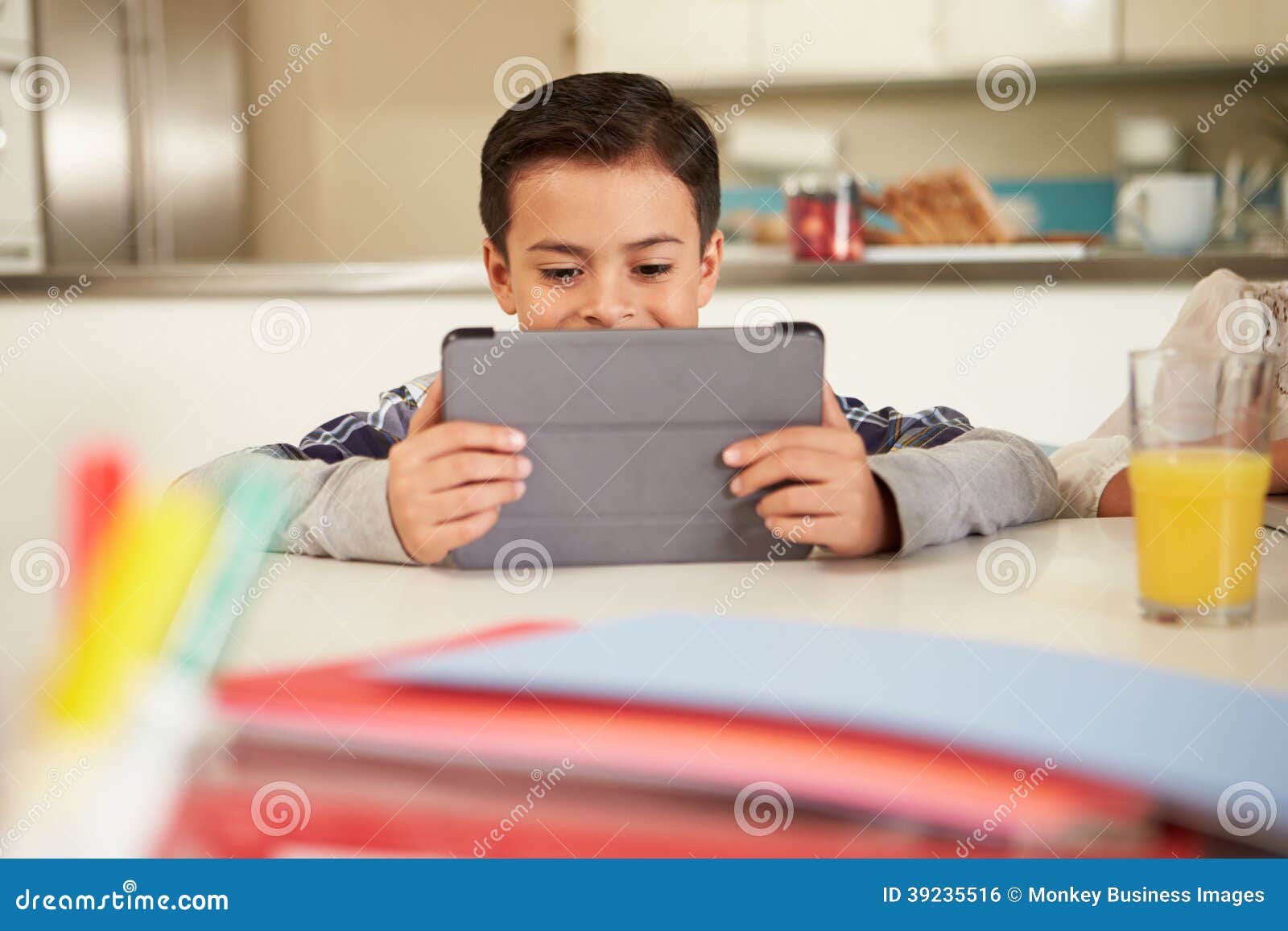 Hispanic Boy Doing Homework at Table Using Digital Tablet Stock Photo ...