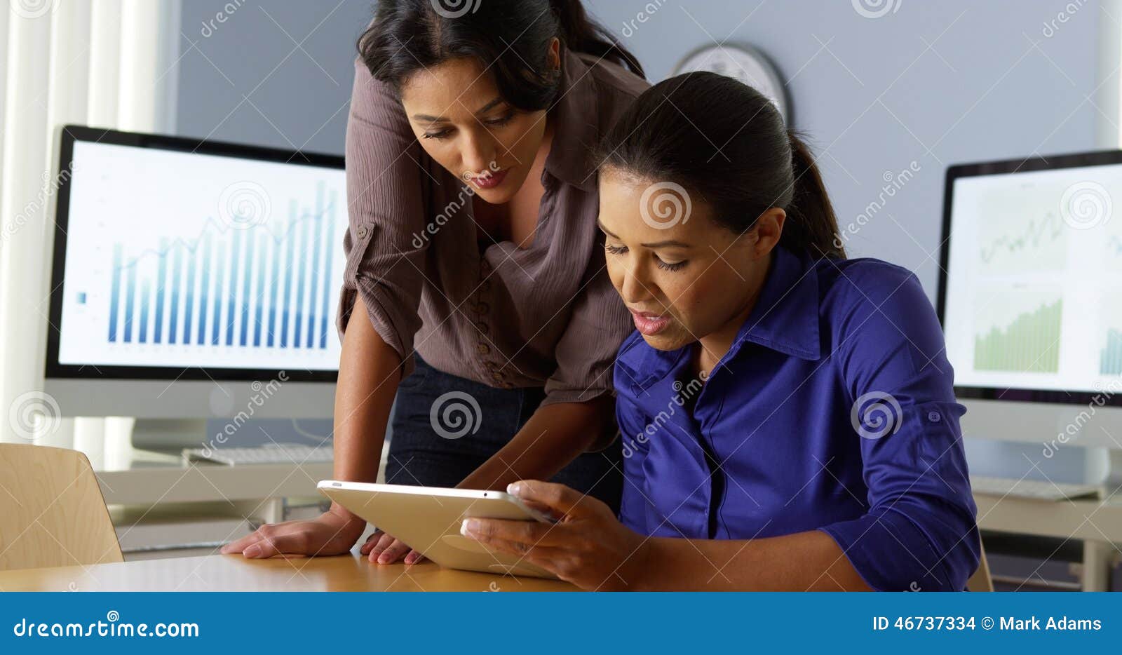 Hispanic Business Women Working with Colleague on Tablet Computer Stock ...