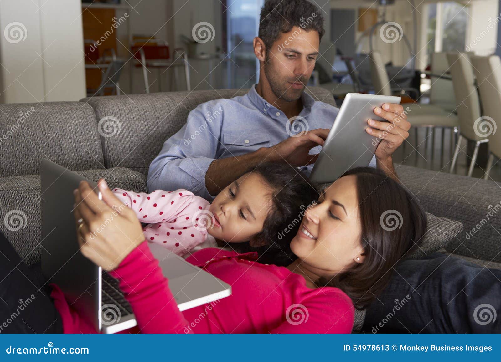 Hispanic Family on Sofa Using Laptop and Digital Tablet Stock Image ...