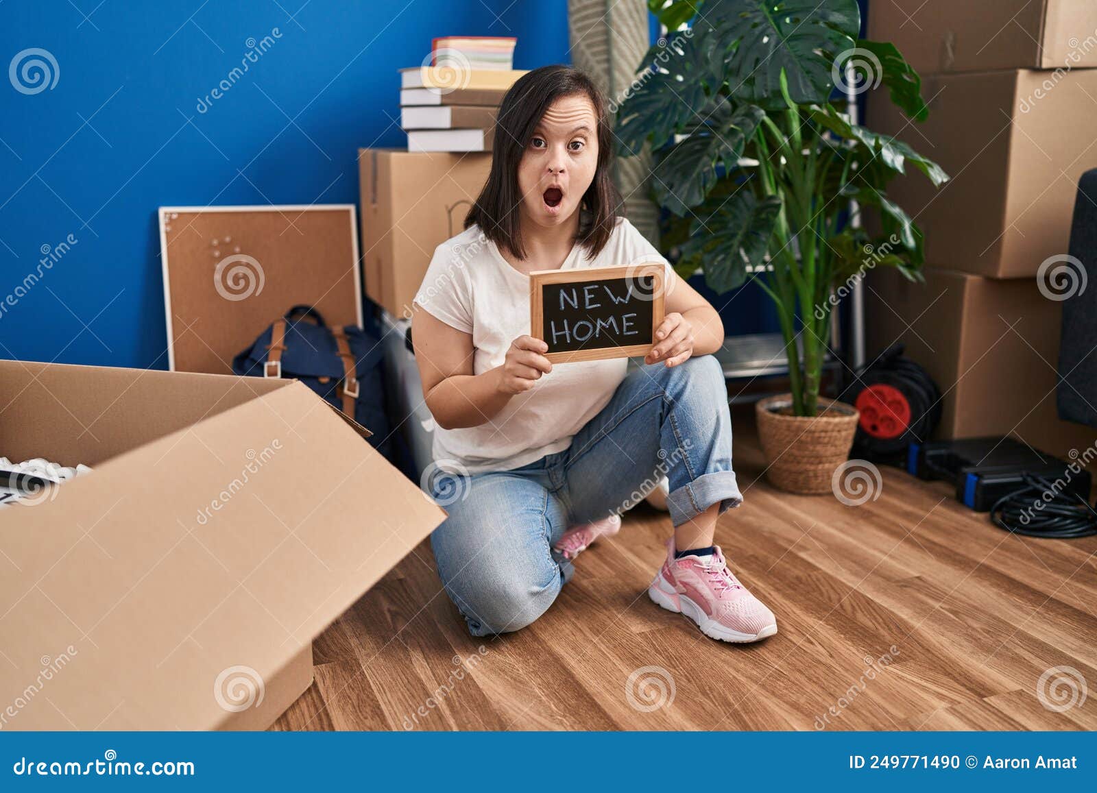 Hispanic Girl With Down Syndrome Sitting On The Floor At New Home