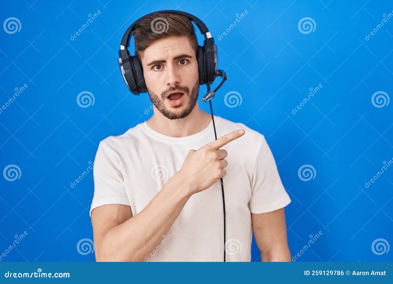Hispanic Man With Beard Listening To Music Wearing Headphones Surprised