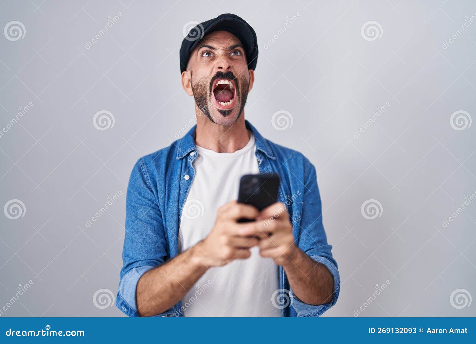 Hispanic Man With Beard Using Smartphone Typing Message Angry And Mad