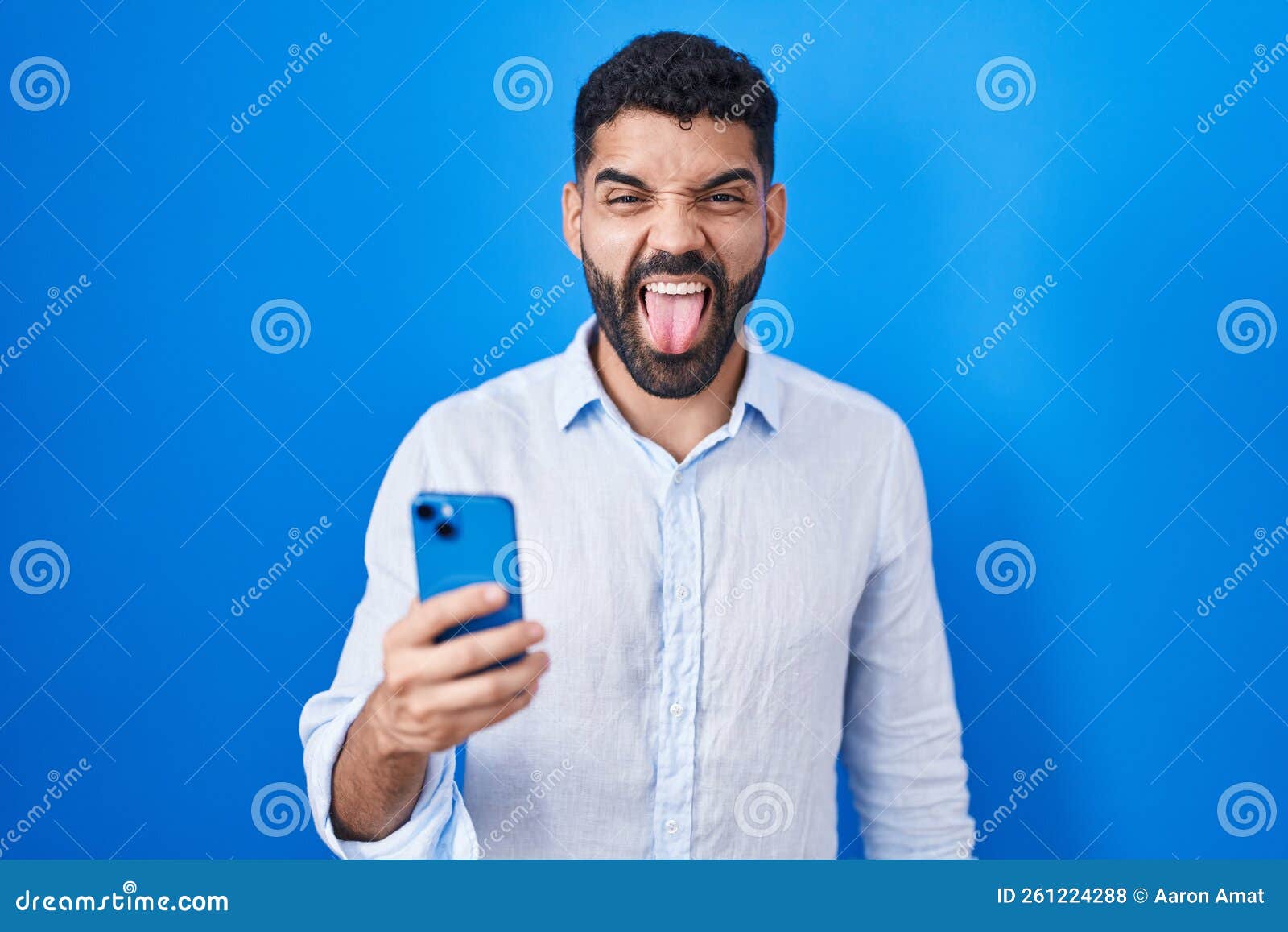 Hispanic Man With Beard Using Smartphone Typing Message Sticking Tongue