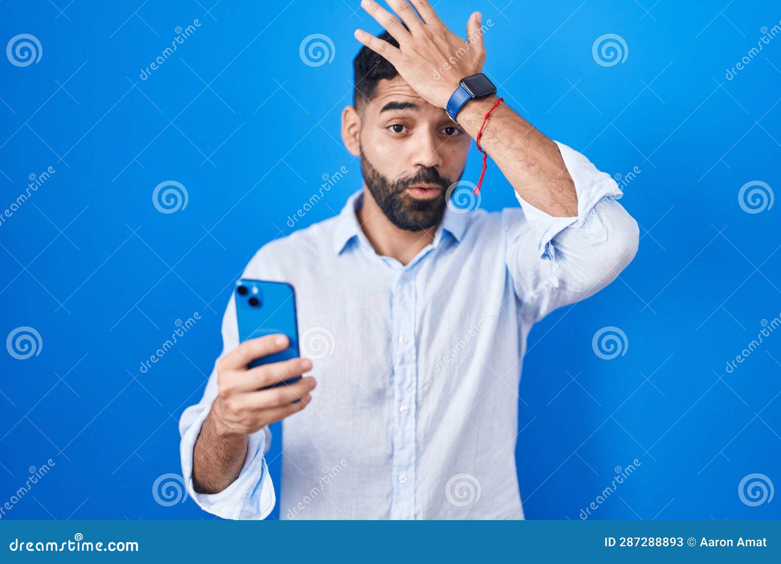 Hispanic Man With Beard Using Smartphone Typing Message Surprised With