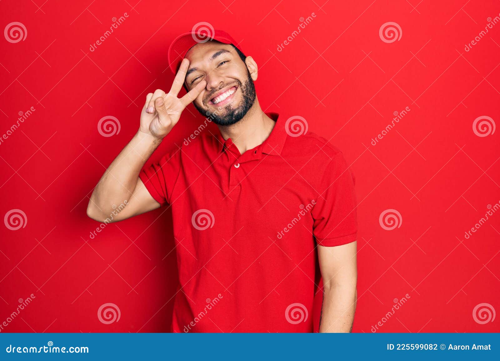 Hispanic Man With Beard Wearing Delivery Uniform And Cap Doing Peace