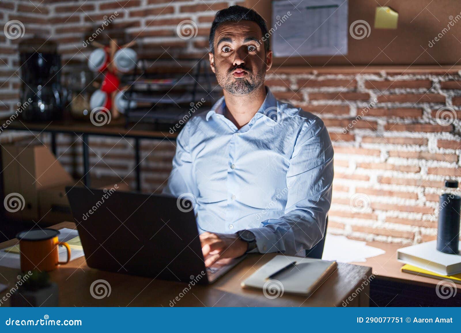 Hispanic Man with Beard Working at the Office at Night Puffing Cheeks ...