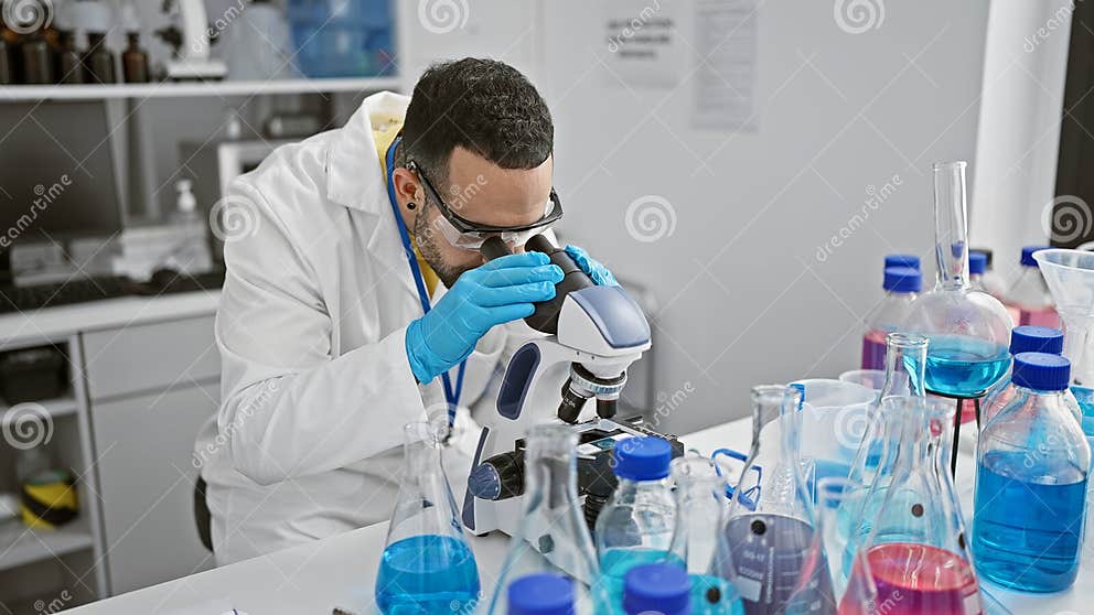 A Hispanic Man in a Lab Analyzing Samples through a Microscope ...