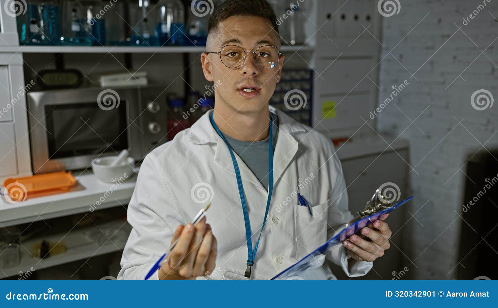 Hispanic Man in Lab Coat Holding Clipboard and Pen in a Laboratory ...