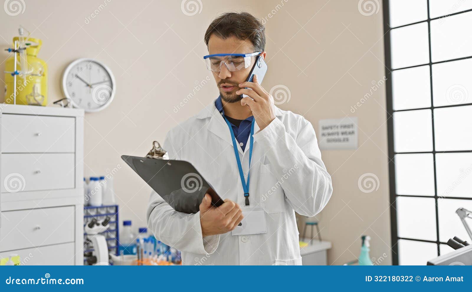 Hispanic Man in Lab Coat Using Tablet and Phone in a Laboratory Setting ...