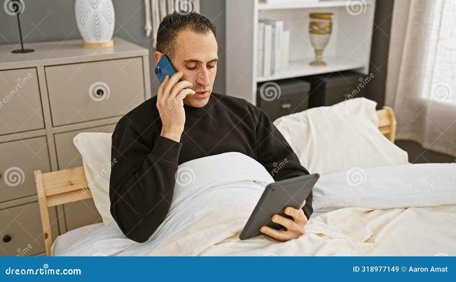 Hispanic Man Multitasking with Smartphone and Tablet while Reclining on ...