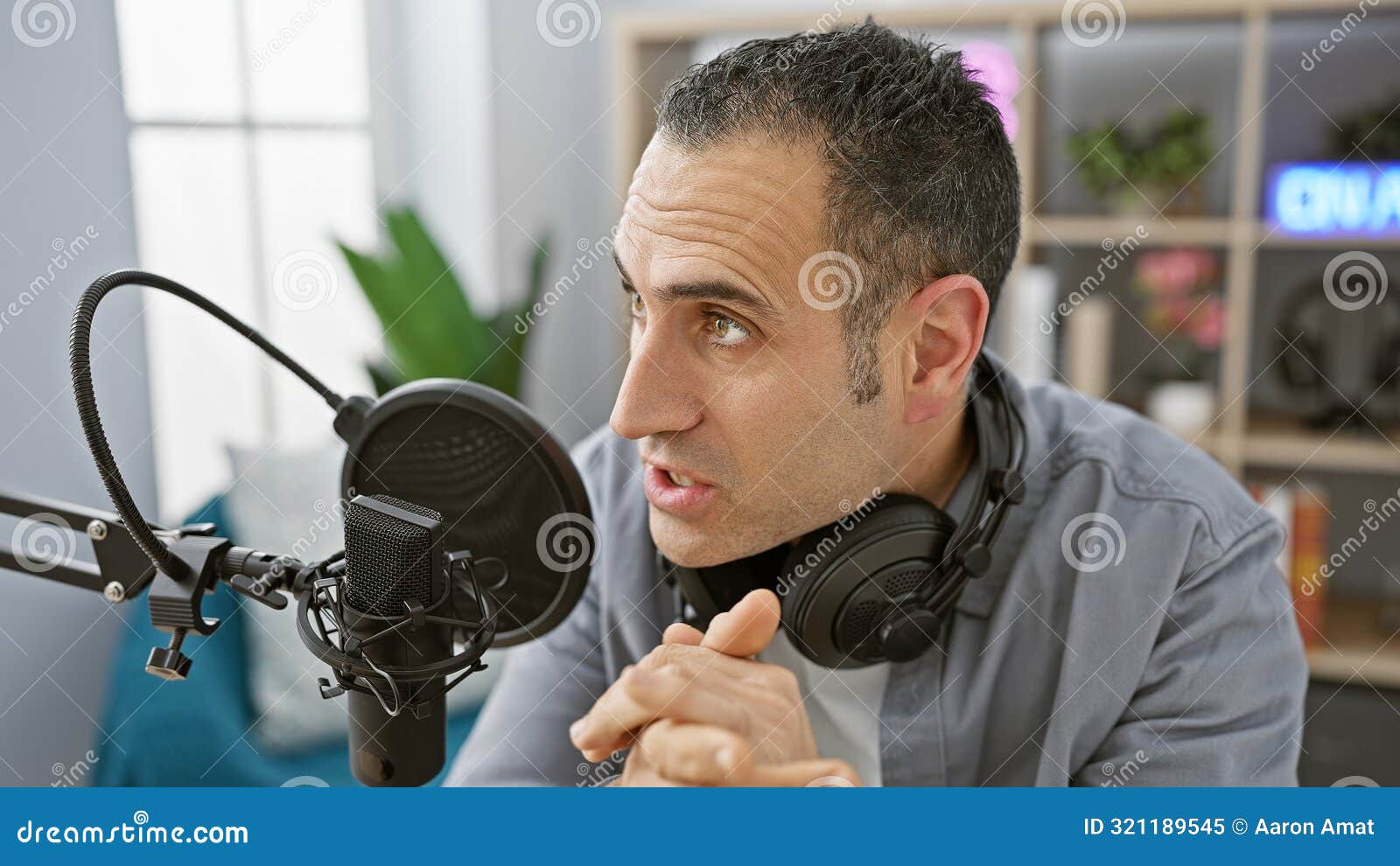 Hispanic Man Speaking into Microphone in a Radio Studio, Conveying ...