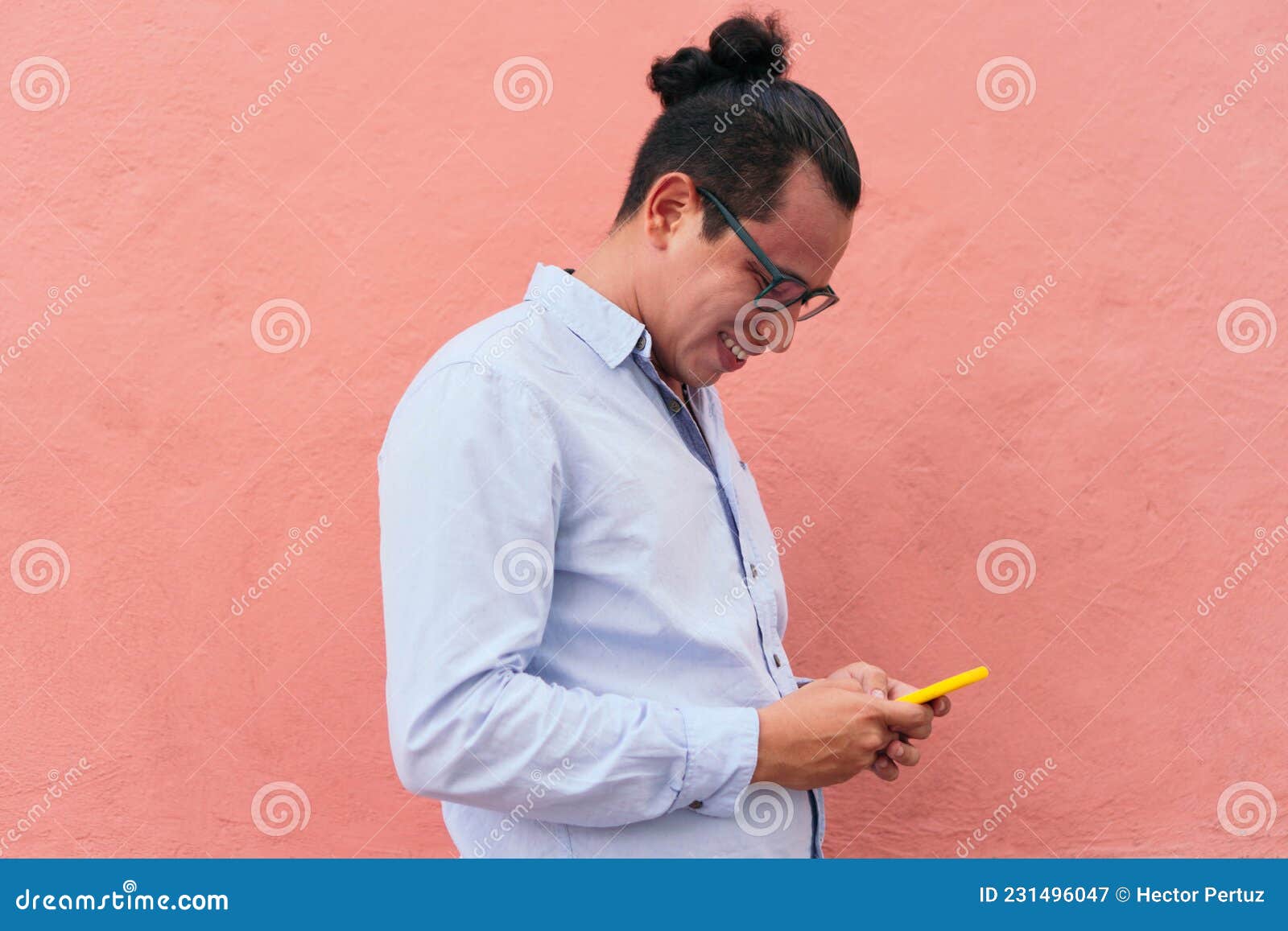 Hispanic Man Standing Checking Cell Phone in Front of Pink Wall Stock ...
