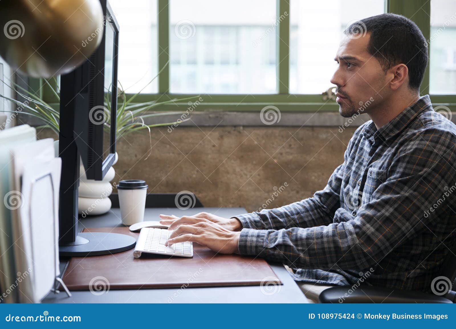 Hispanic Man Working at a Computer in an Office, Side View Stock Photo ...