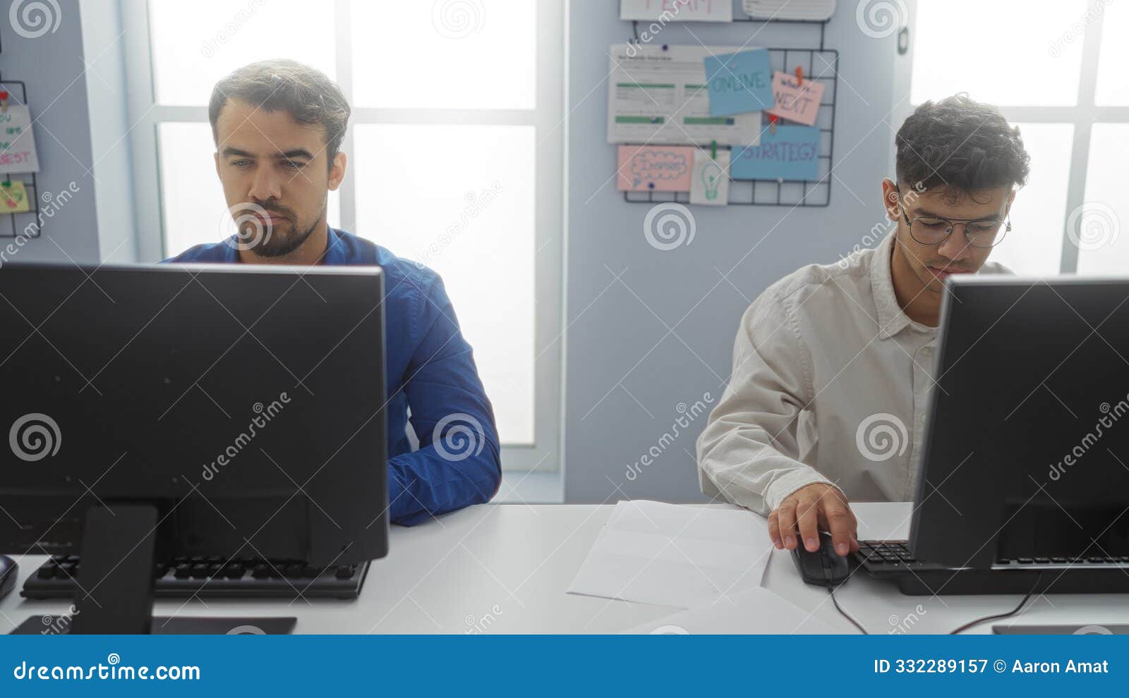 Hispanic Men Working Together in an Office, Focused on Computer Screens ...