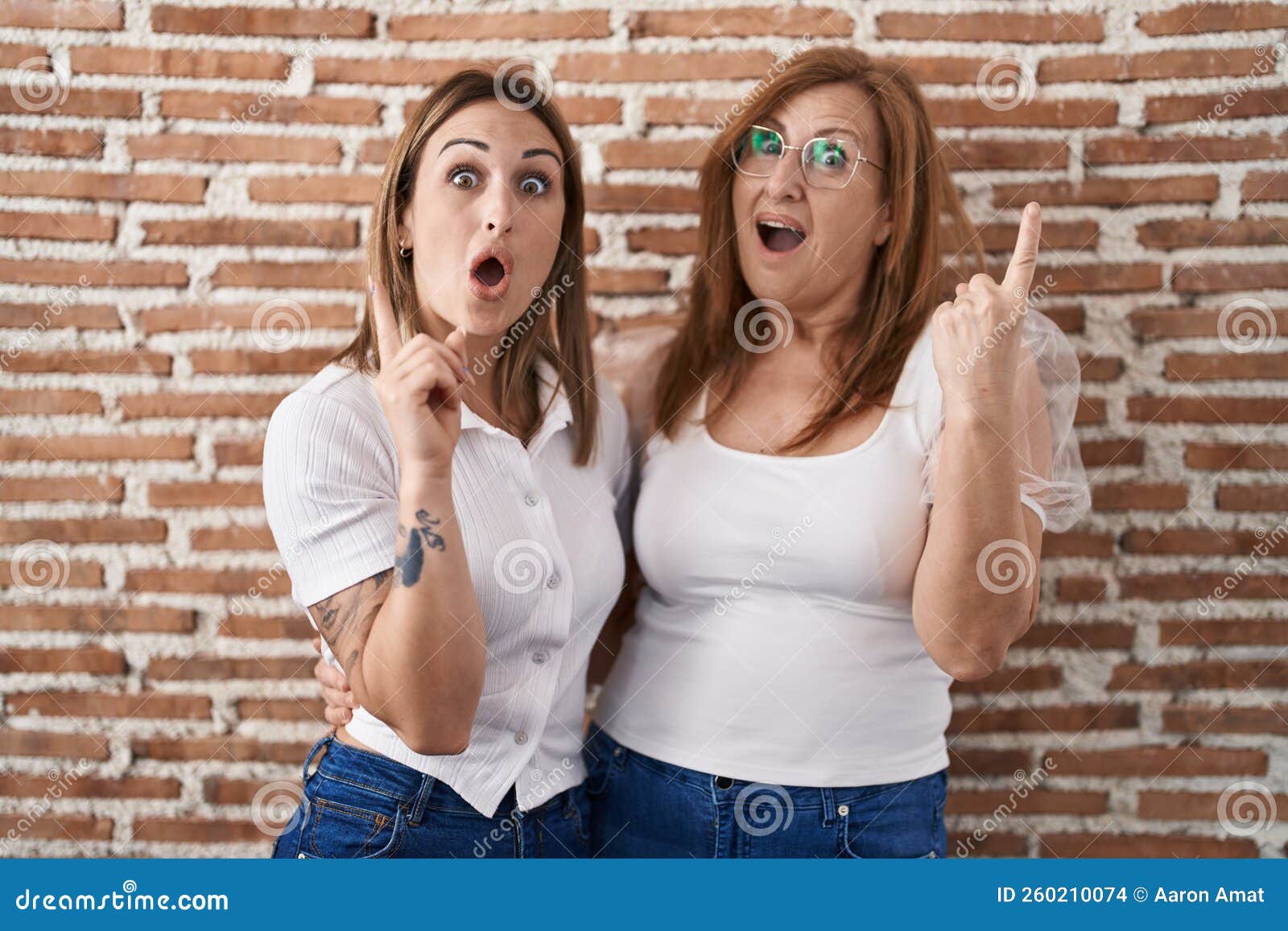 Hispanic Mother And Daughter Wearing Casual White T Shirt Pointing