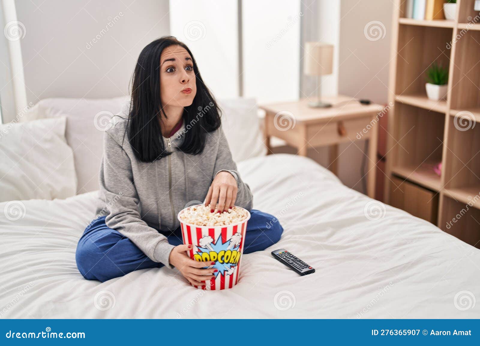Hispanic Woman Eating Popcorn Watching A Movie On The Bed Puffing