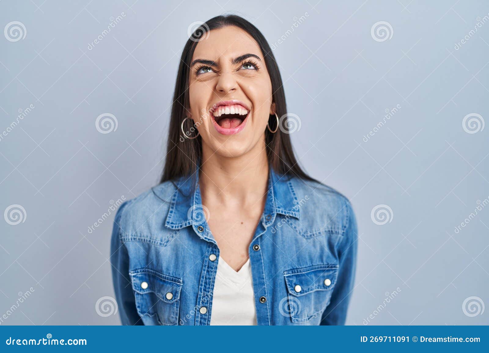 Hispanic Woman Standing Over Blue Background Angry And Mad Screaming