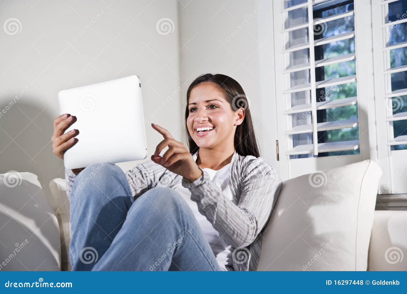 Hispanic Woman Using Tablet Computer on Couch Stock Photo - Image of ...