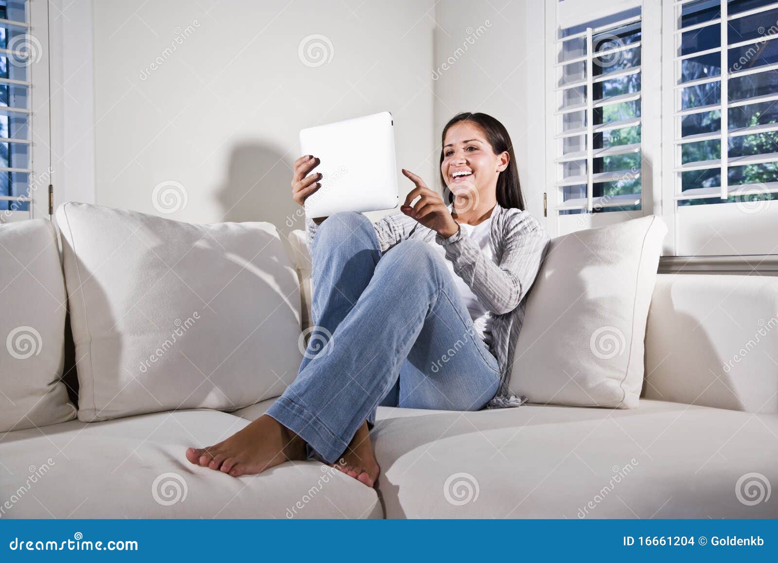 Hispanic Woman Using Tablet Computer on Couch Stock Photo - Image of ...