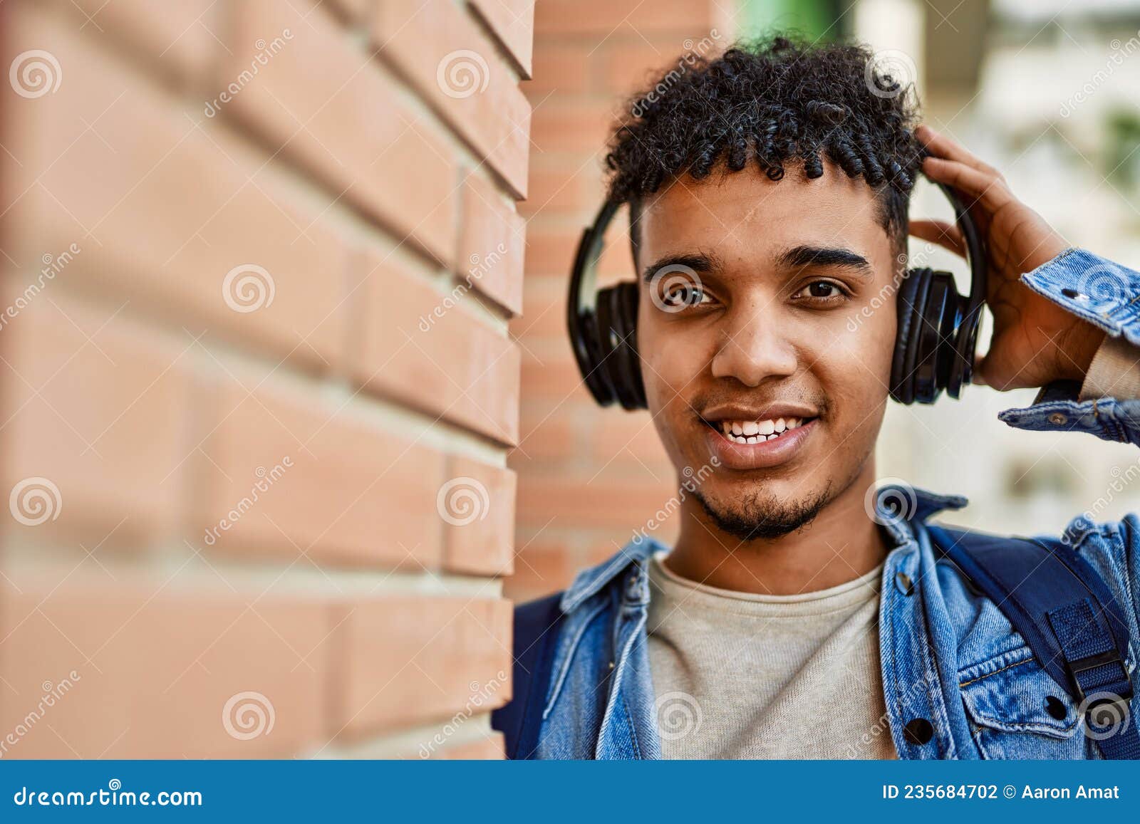 Hispanic Young Man Listening To Music Wearing Headphones Leaning On