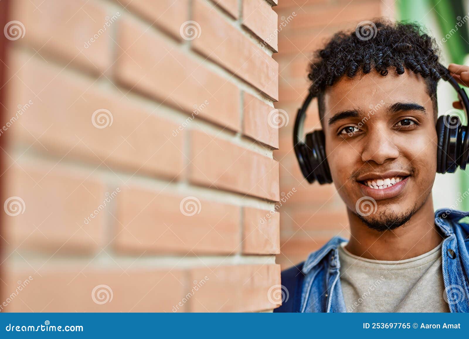 Hispanic Young Man Listening To Music Wearing Headphones Leaning On