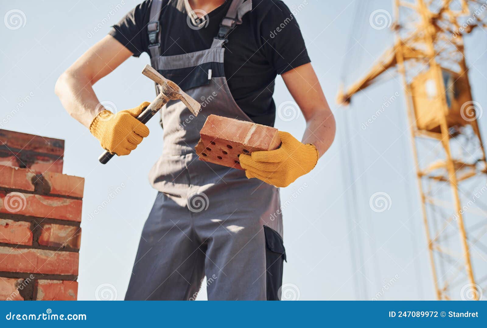 Holding Brick and Using Hammer. Construction Worker in Uniform and ...