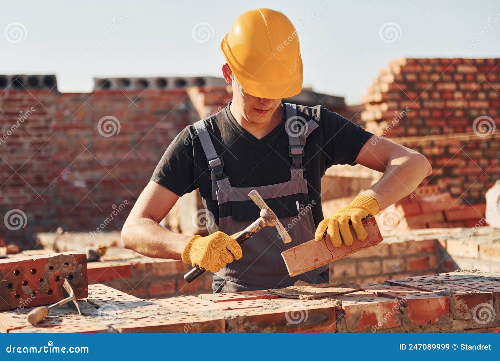 Holding Brick and Using Hammer. Construction Worker in Uniform and ...