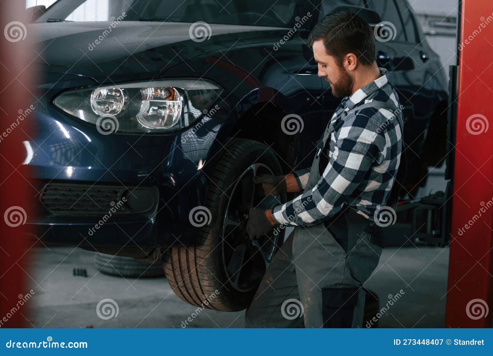 Holding and Changing New Tire. Man in Uniform is Working in the Auto ...