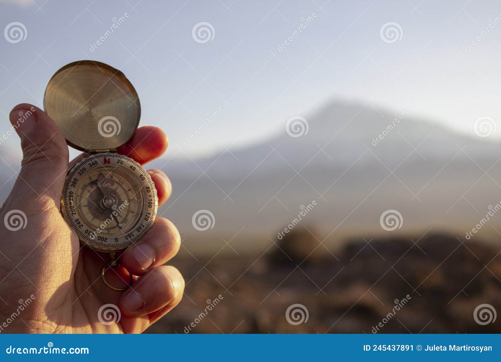 Holding a Compass Against the Backdrop of a Mountain at Sunset Stock ...