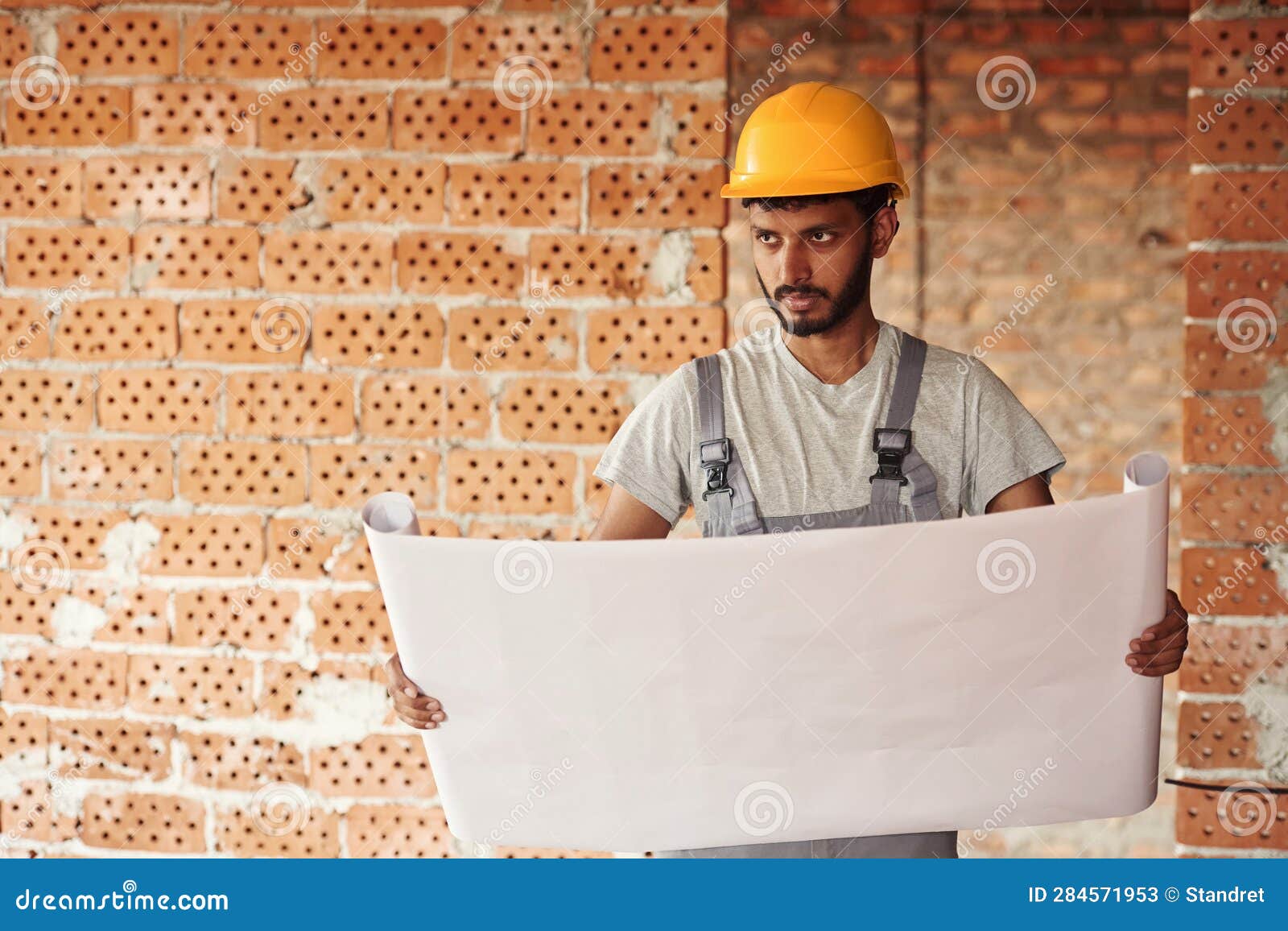 Showing and Holding Little Shovel and Brick. Handsome Indian Man is on ...
