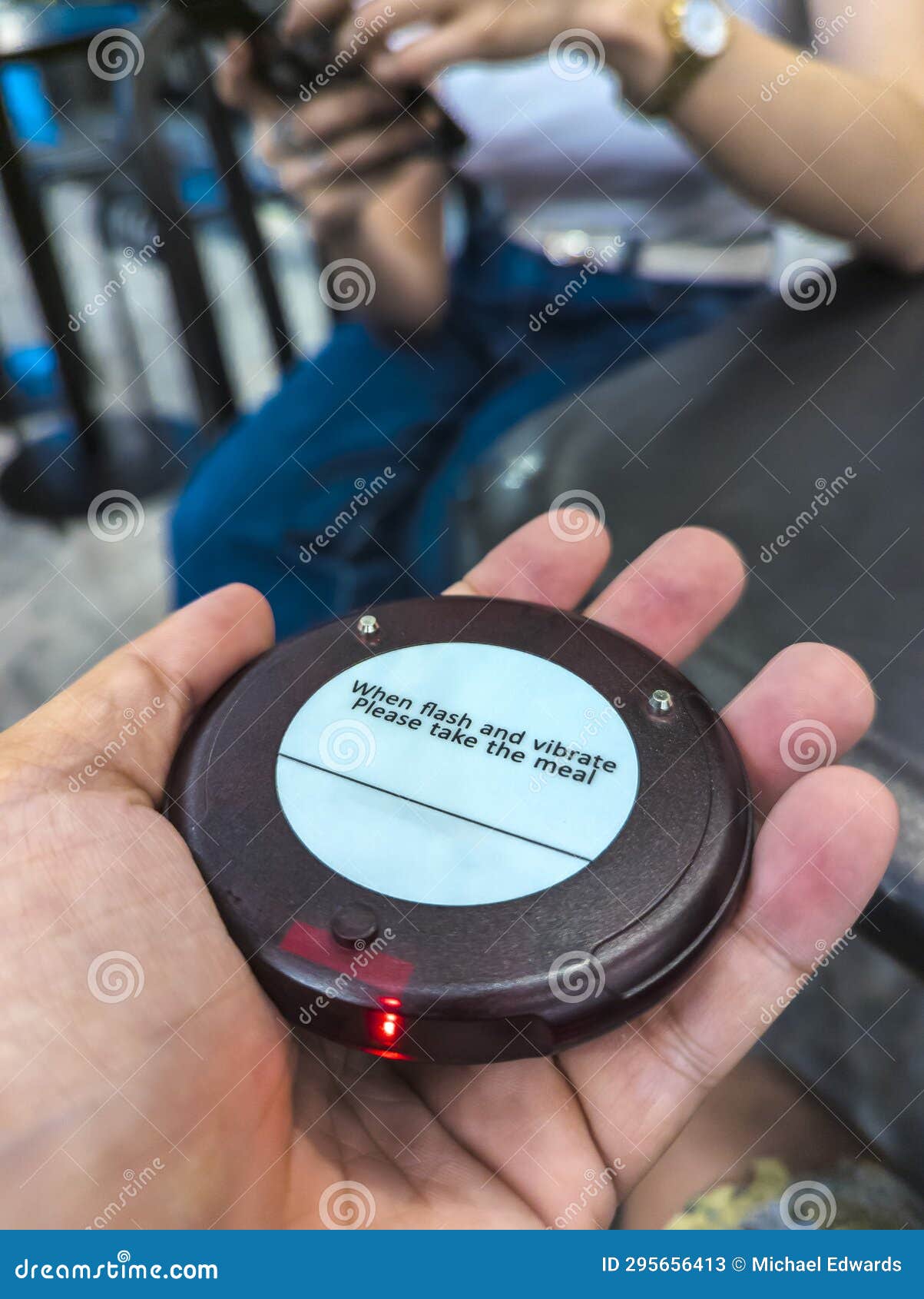 Holding an Electronic Restaurant Pager, Also Known As a Buzzer or ...