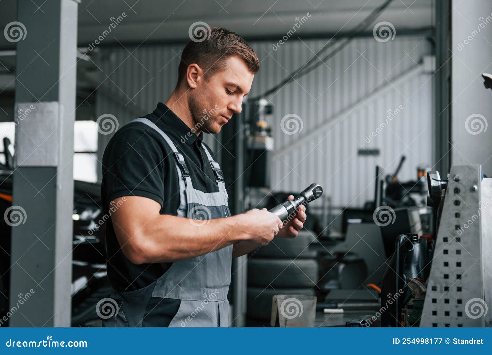 Holding Tool. Man in Uniform is Working in the Auto Service Stock Image ...