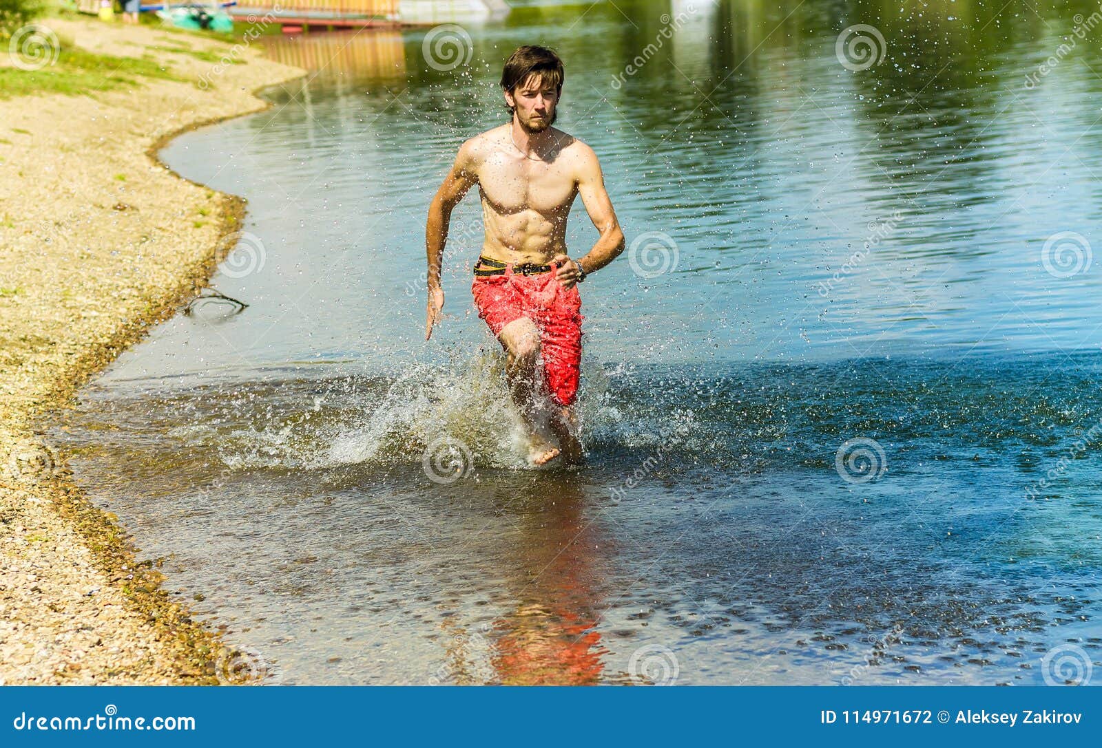 Hombre Joven Coreano Que Corre En El Agua Con Una Sonrisa Y Un Torso Desnudo Foto De Archivo