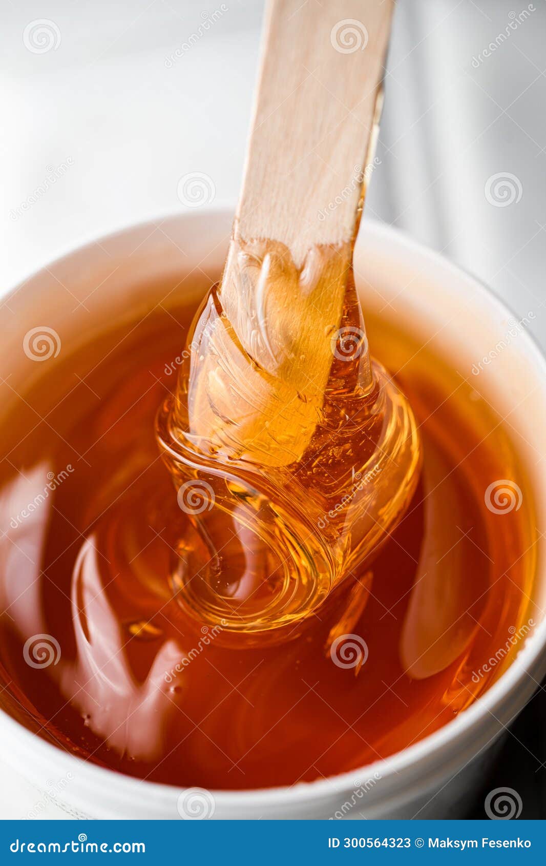 Honey-brown Sugaring Paste in a White Plastic Container with a Wooden ...