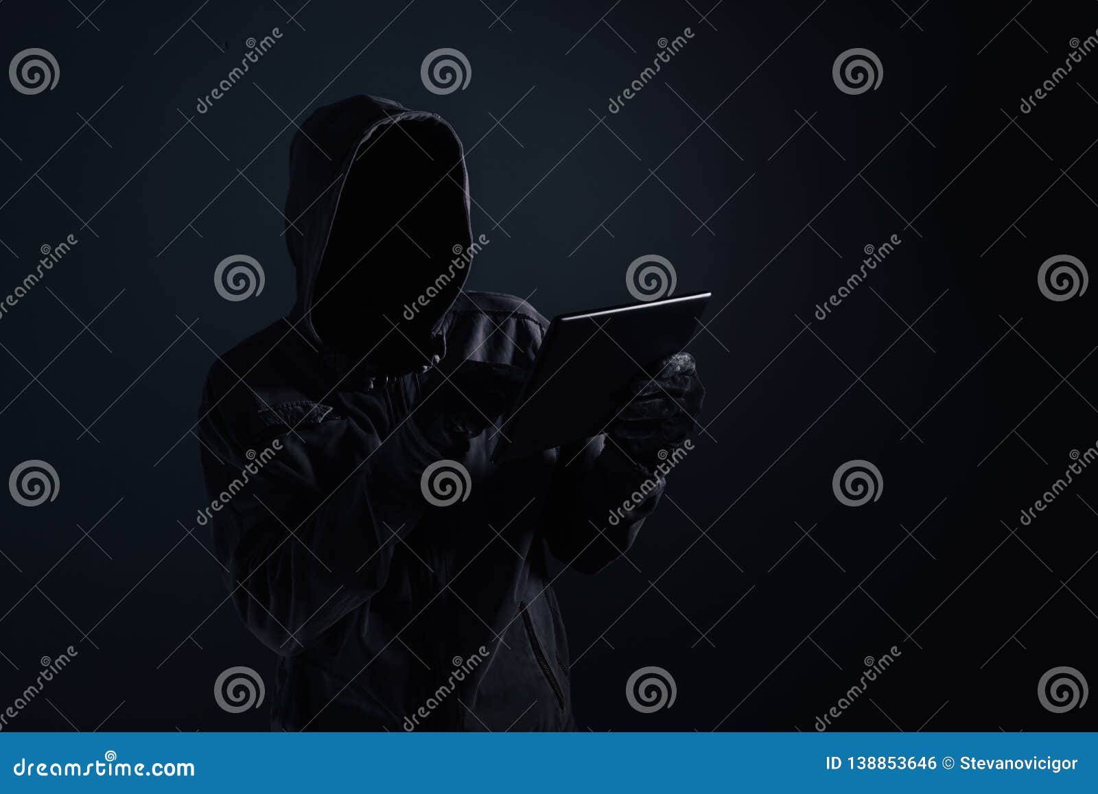 Hooded Computer Hacker with Obscured Face Using Digital Tablet Stock ...