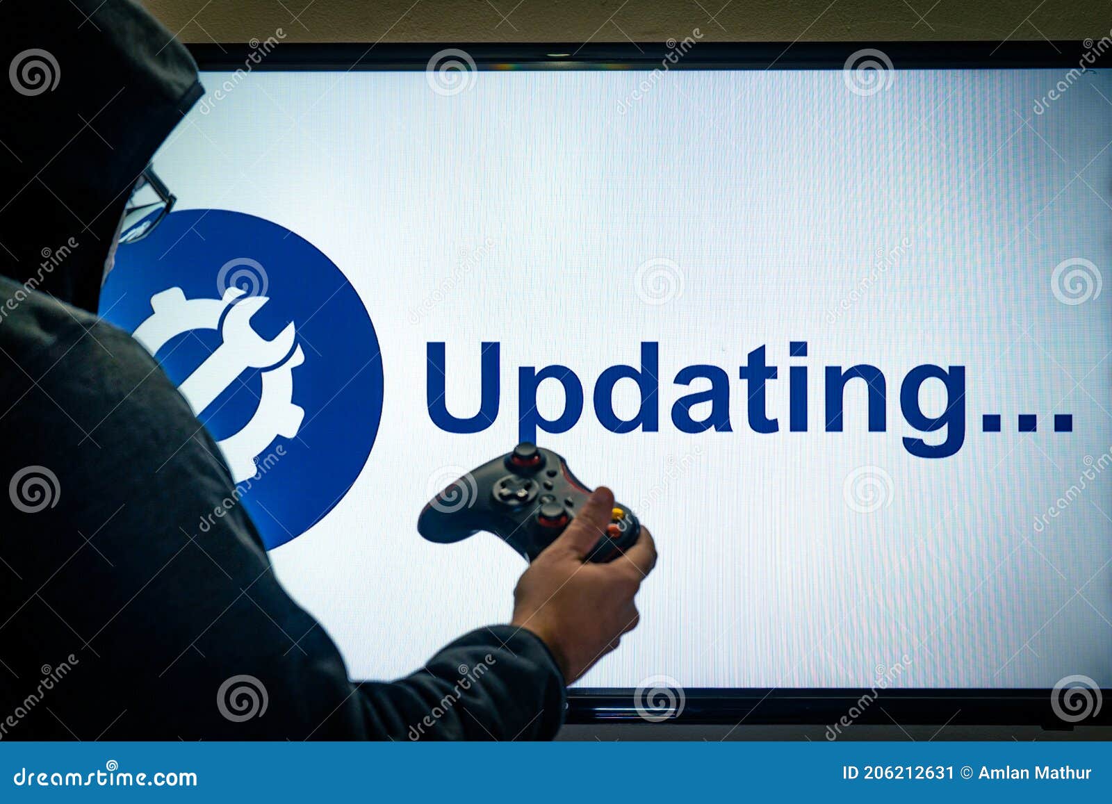 Hooded Man Holding a Gaming Controller in Front of a Screen Showing an ...