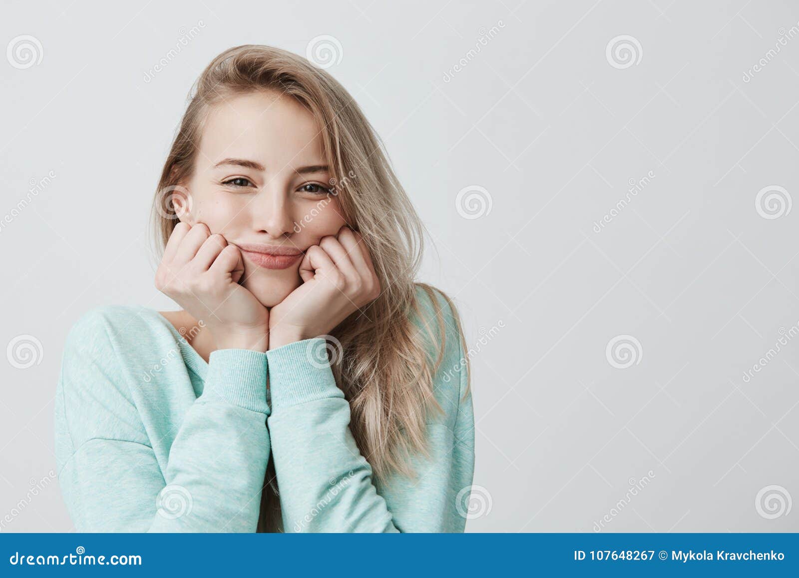 Horizontal Portrait Of Positive Caucasian Female Model With Blonde Hair Resting Her Head On