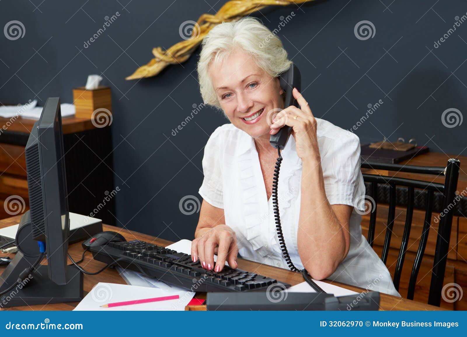 Hotel Receptionist Using Computer and Phone Stock Photo - Image of ...