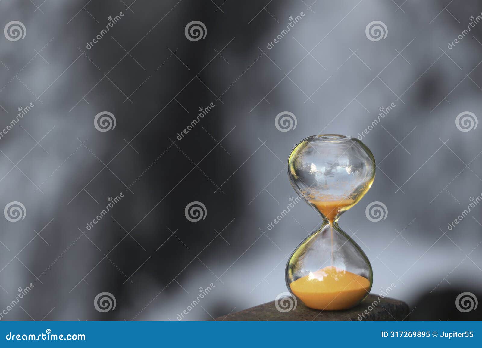 An Hourglass with Blur Waterfall in Background. Fallen Orange Sand ...