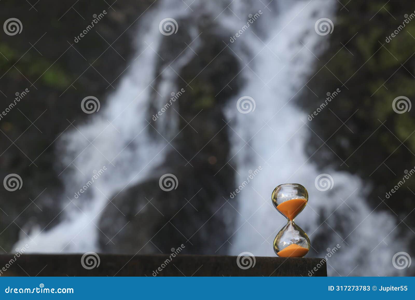 An Hourglass with Blur Waterfall in Background. Fallen Orange Sand ...