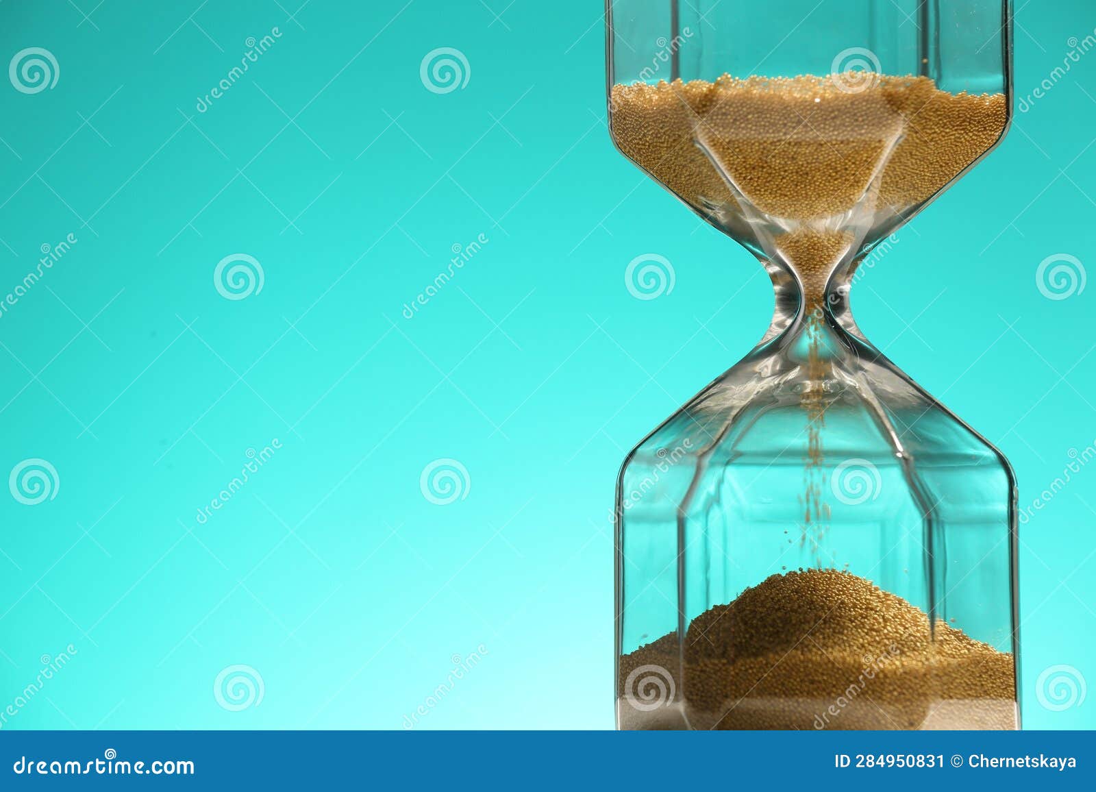 Hourglass with Flowing Sand on Turquoise Background, Closeup. Space for ...