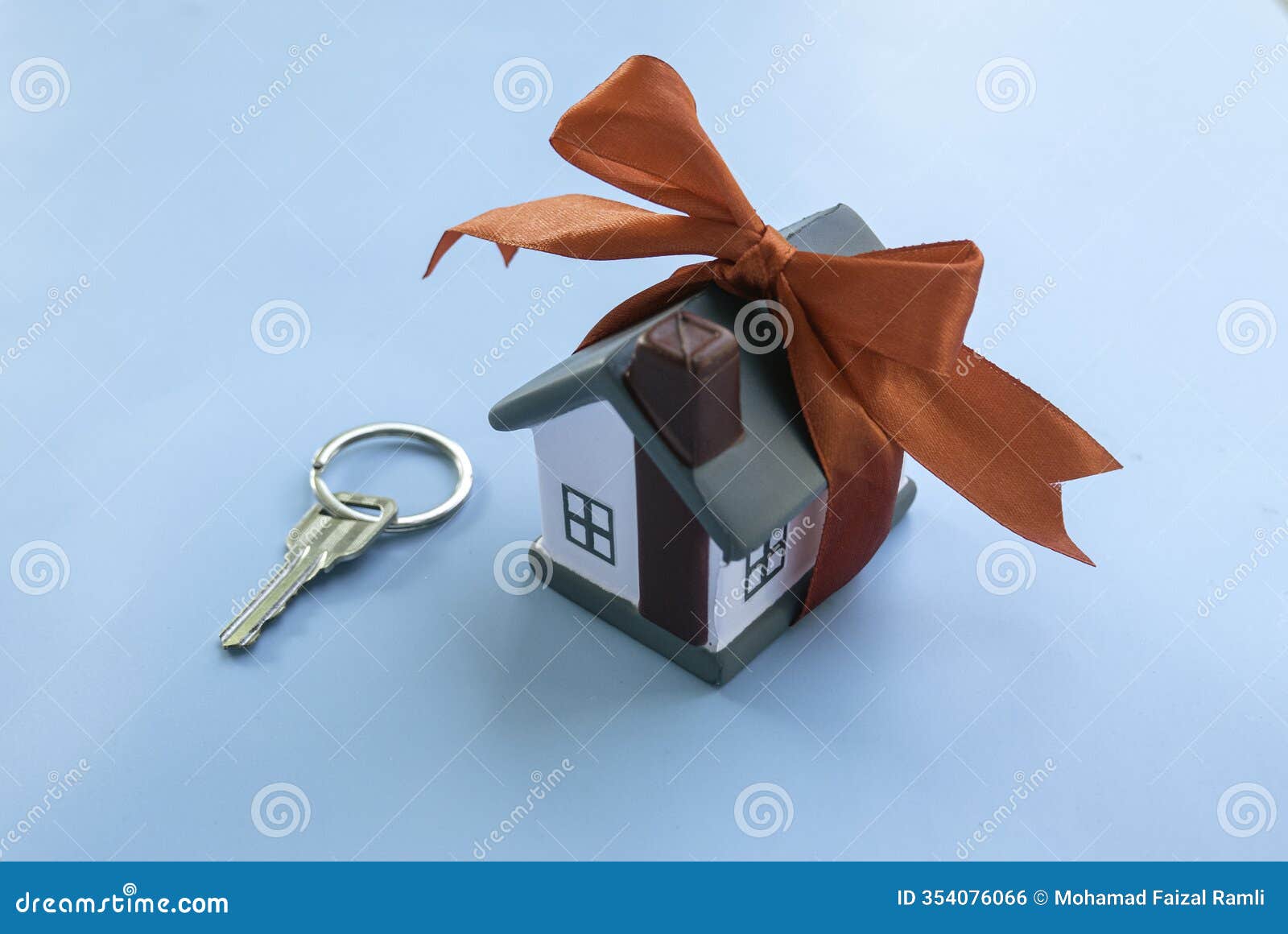 House Key with Miniature House Gift Wrapped with Red Ribbon on Blue ...