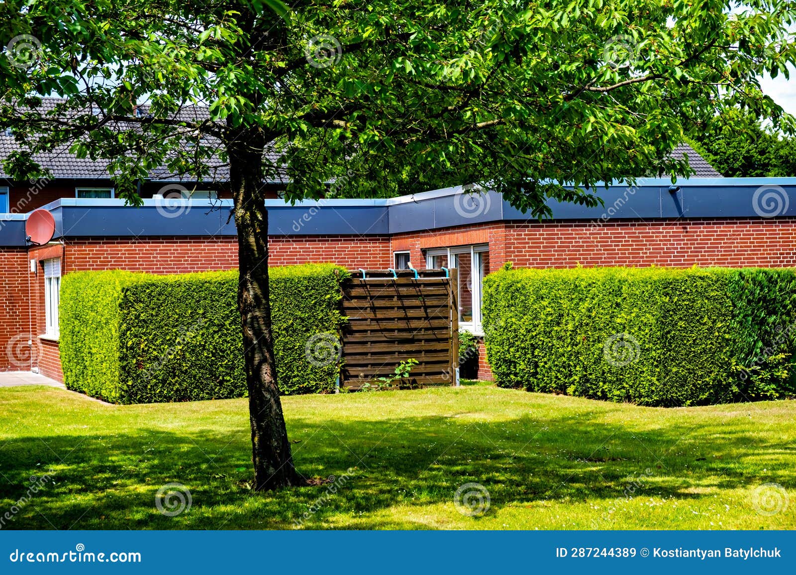 House Surrounded by Hedges in the Middle of Green Yard with Blue Sky in ...