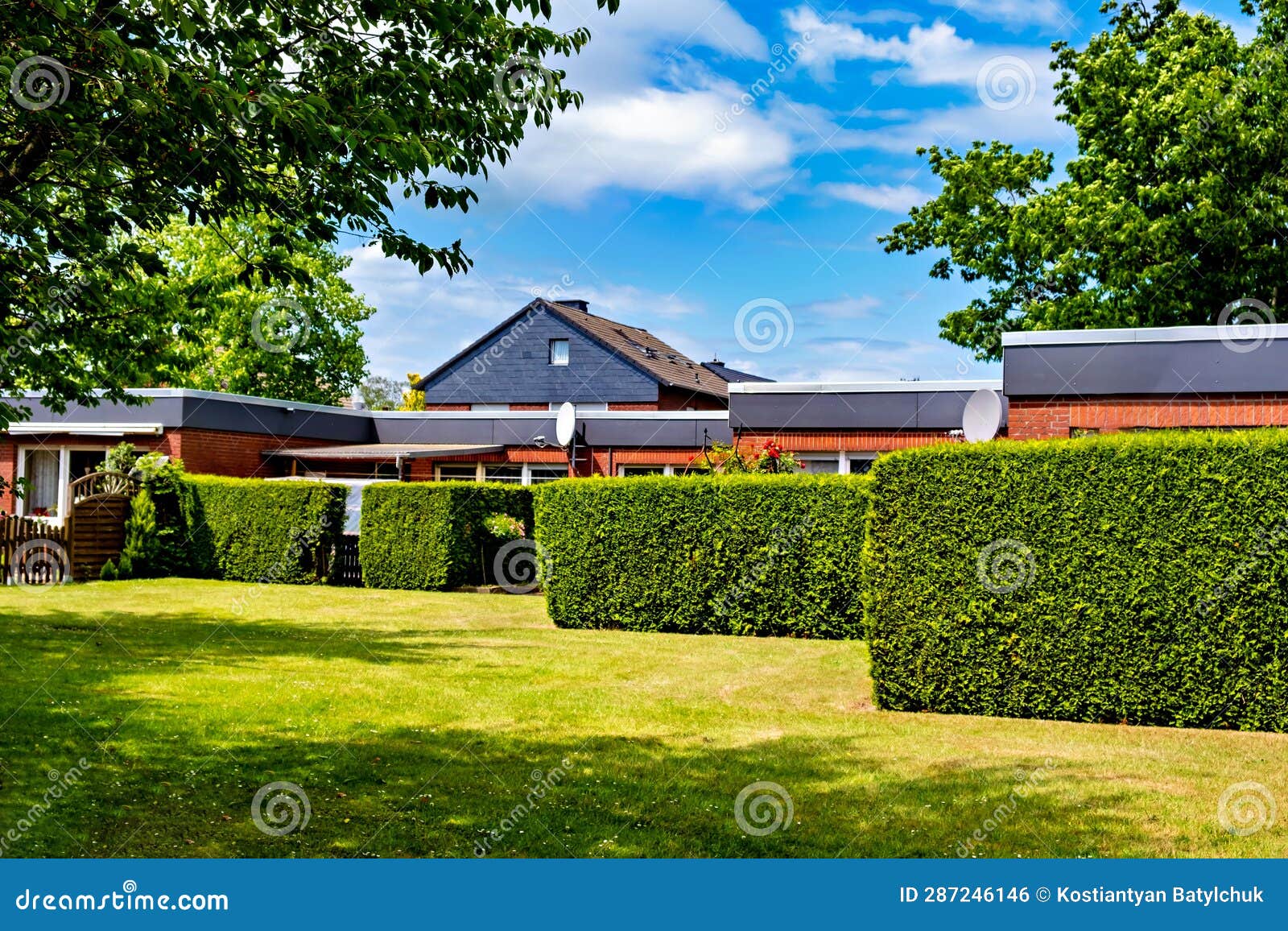 House Surrounded by Hedges in the Middle of Green Yard with Blue Sky in ...