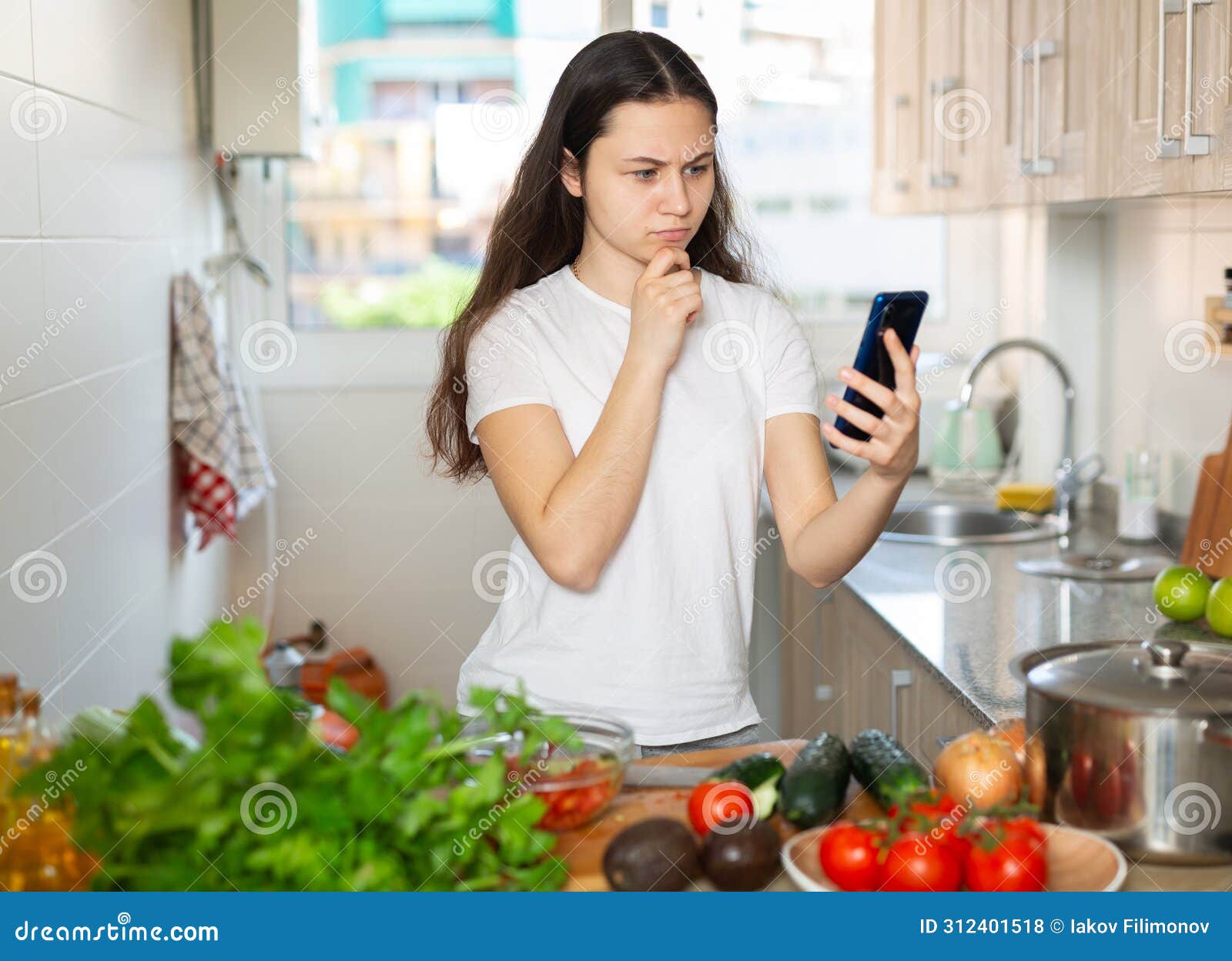 Housewife Using Mobile Phone during Cooking at Kitchen Stock Photo ...