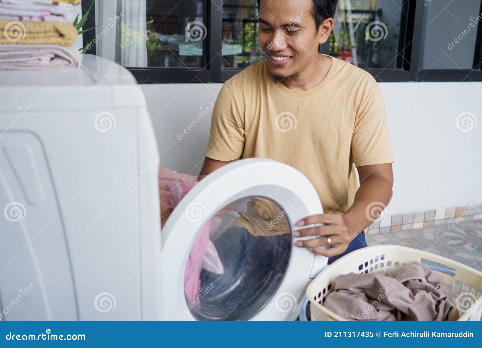 Housework. Asian Man Loading Clothes into Washing Machine Stock Image ...