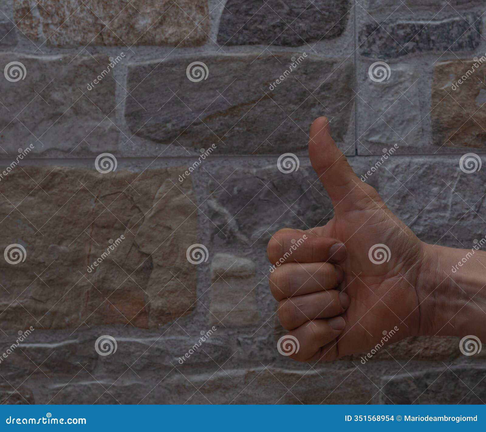Human Hand Displays a Thumbs Up Sign Against a Textured Stone Wall ...