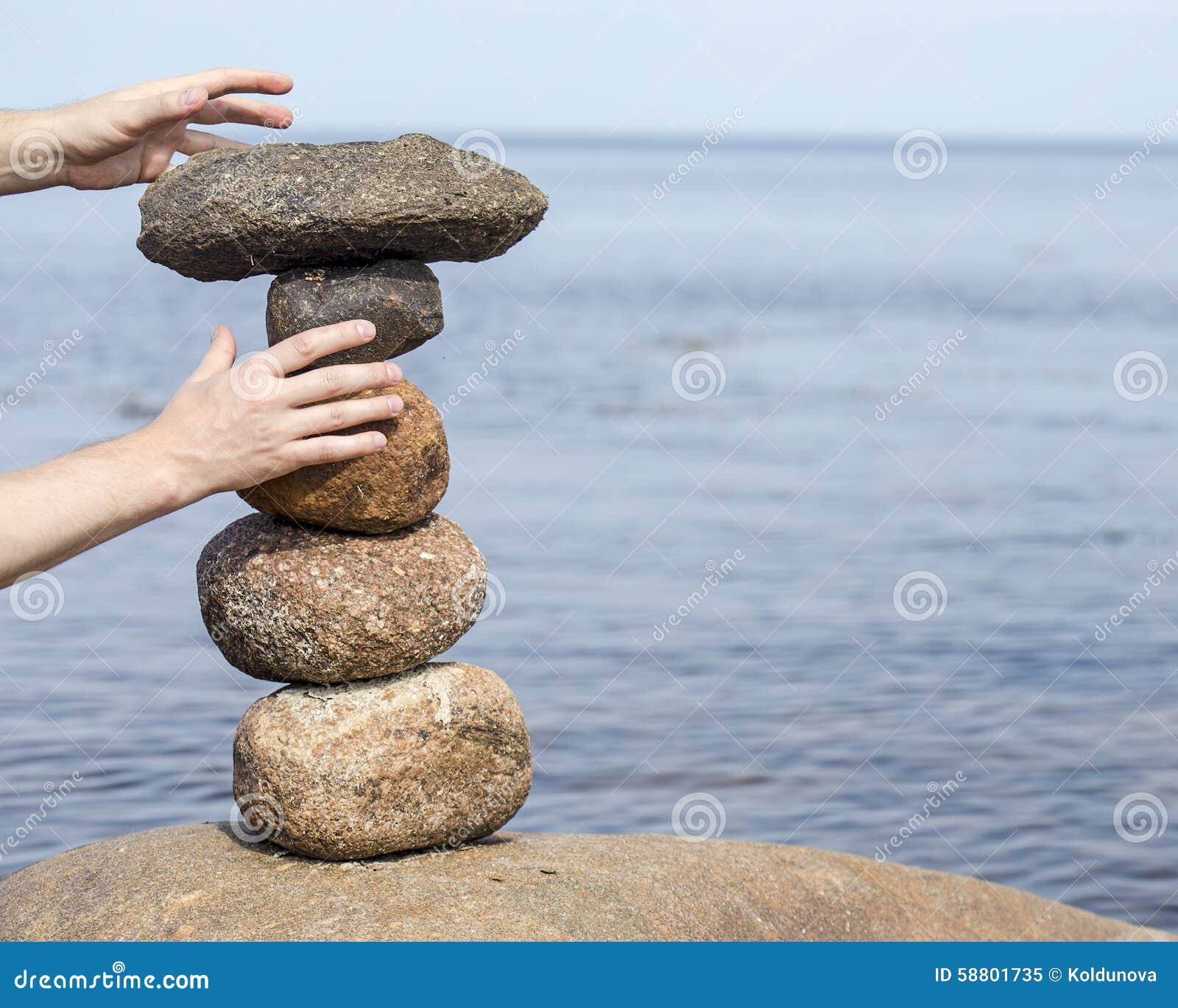 Human Hand Making Stack of Large Round Stones Near the Water Stock ...